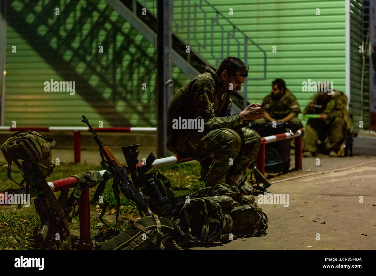 Side view serious soldier writing message in phone while wearing in ...