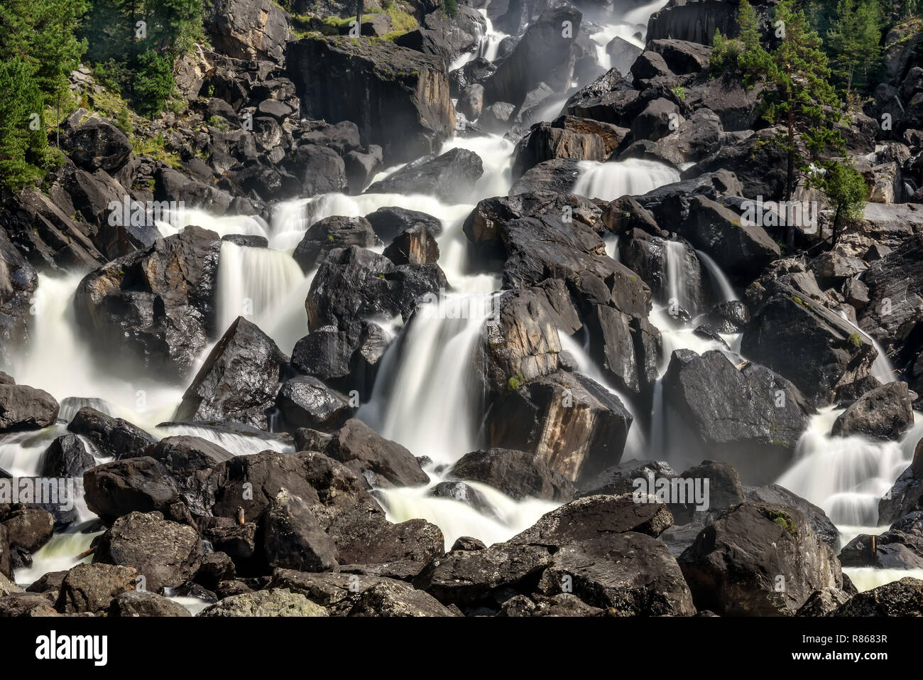 Beautiful waterfall with smooth water falling among the rocks and black ...
