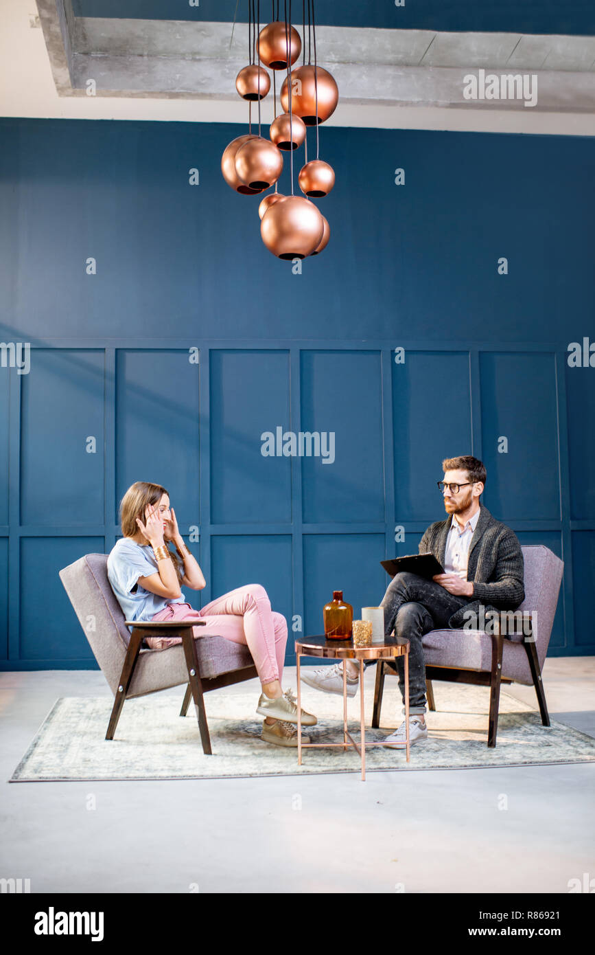 Woman client sitting with male psychologist on the chairs during the ...