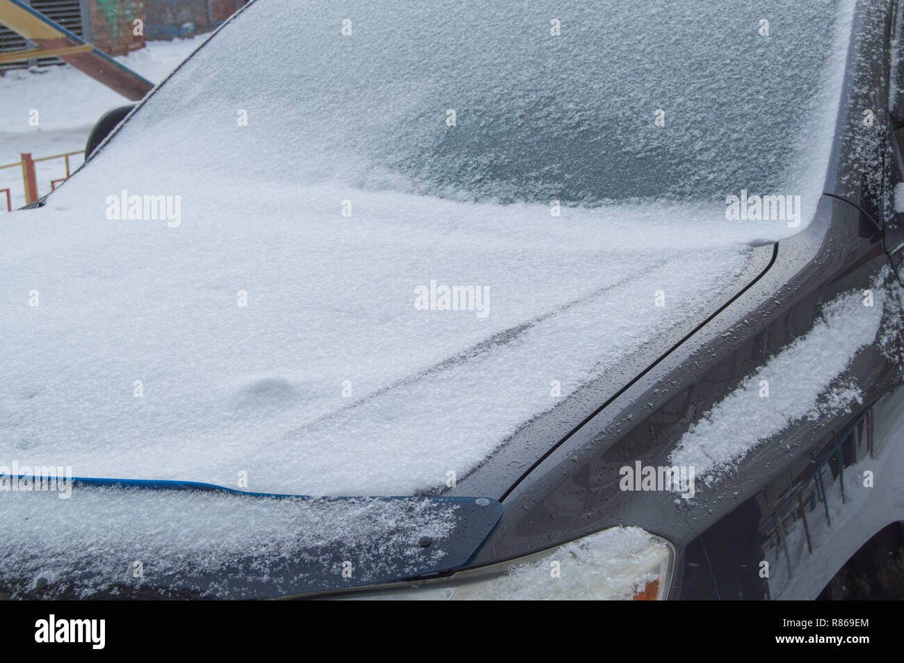 The car is covered with snow on a winter day, front window windshield ...