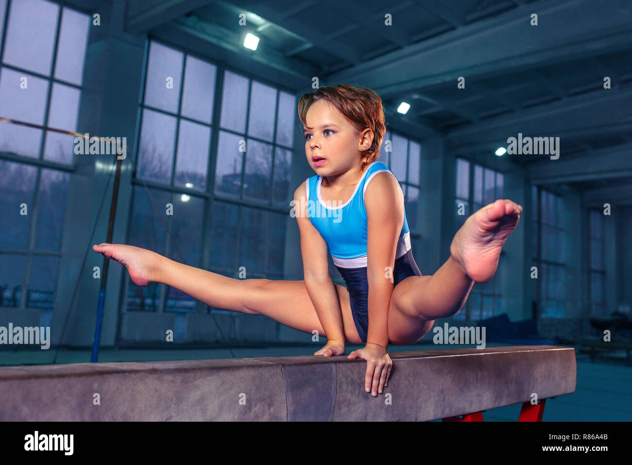 The beautiful little girl is engaged in sports gymnastics on a log at ...
