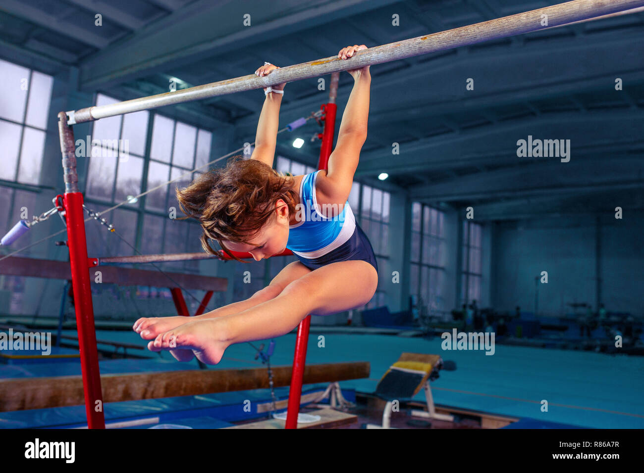 The beautiful little girl is engaged in sports gymnastics on a parallel ...