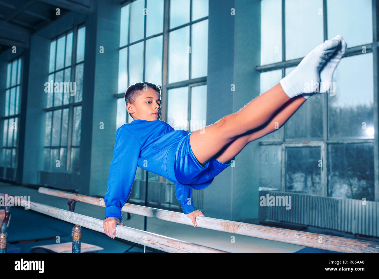 The little boy is engaged in sports gymnastics on a parallel bars at ...
