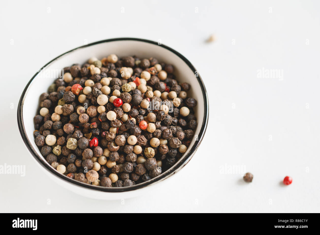 Various kinds of pepper seeds in a white bowl on a white background ...