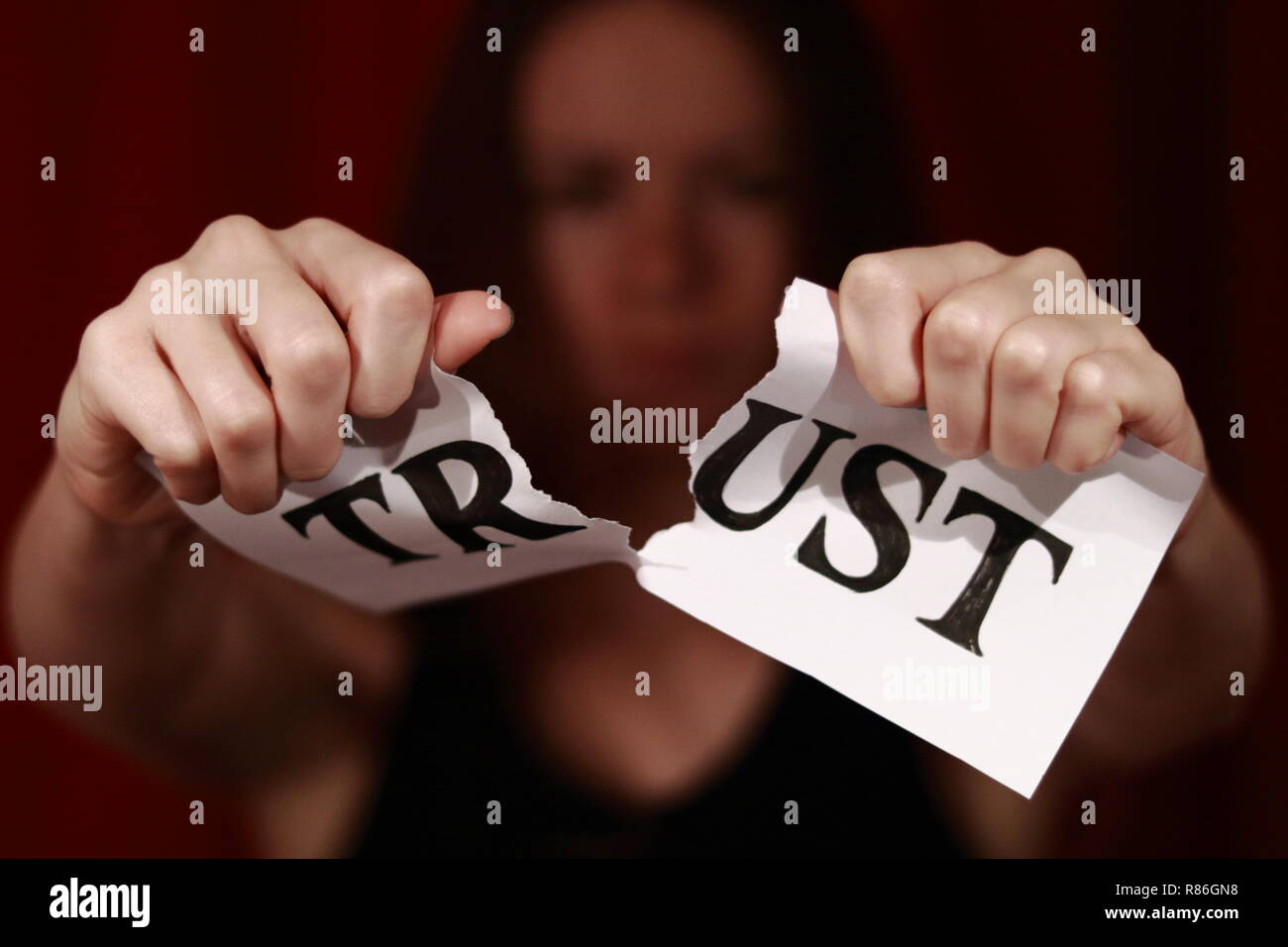 Ripped white paper with drawn letters of "TRUST" on it. Girl ripping ...