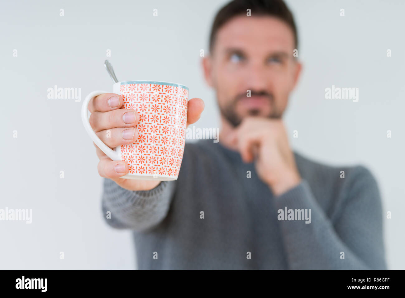 Young man driking cup of coffee over isolated background serious face ...