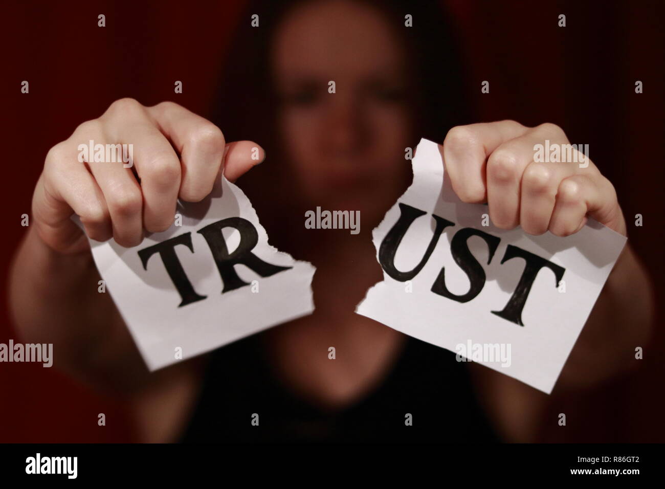 Ripped white paper with drawn letters of "TRUST" on it. Girl ripping ...