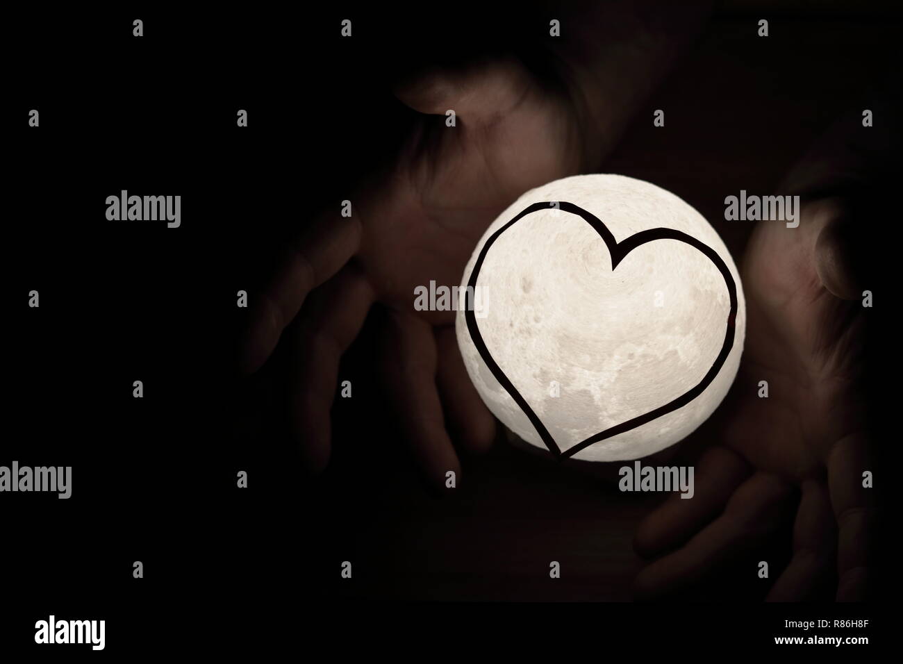 Abstract picture of men hands holding the small moon with strong white ...