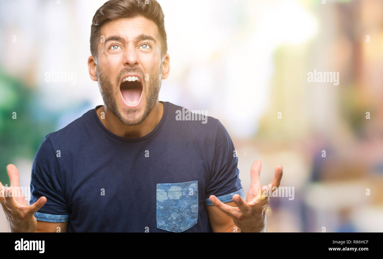 Young handsome man over isolated background crazy and mad shouting and ...