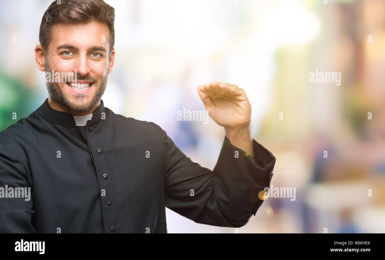 Young catholic christian priest man over isolated background gesturing ...