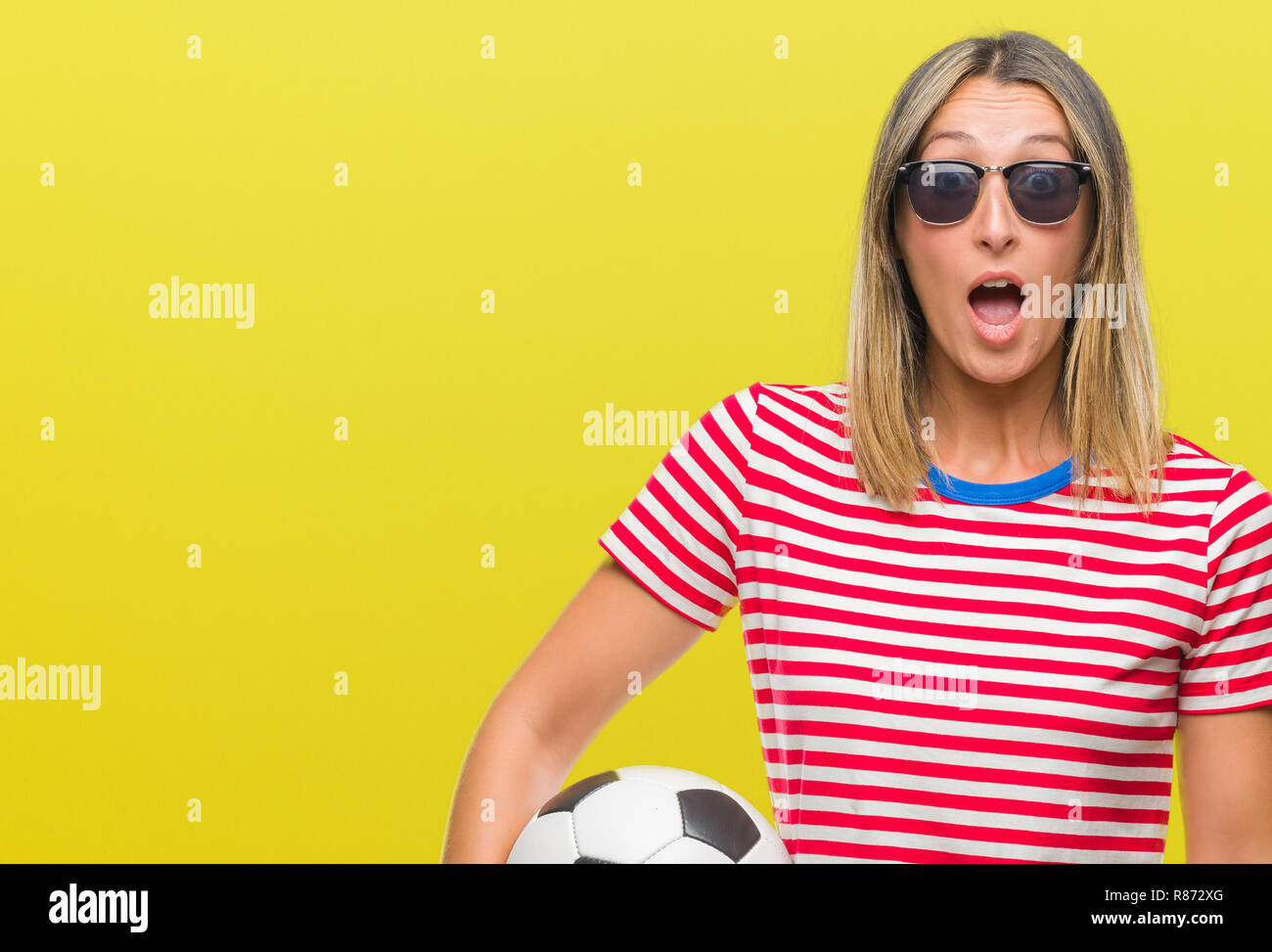 Young beautiful woman holding soccer football ball over isolated ...