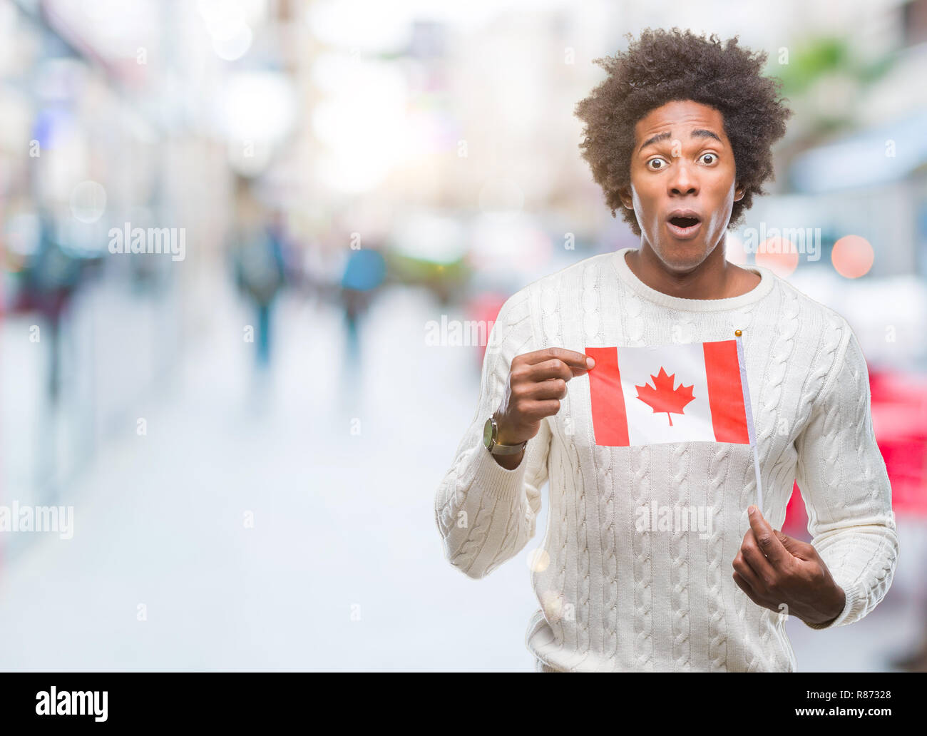Afro american man flag of Canada over isolated background scared in ...