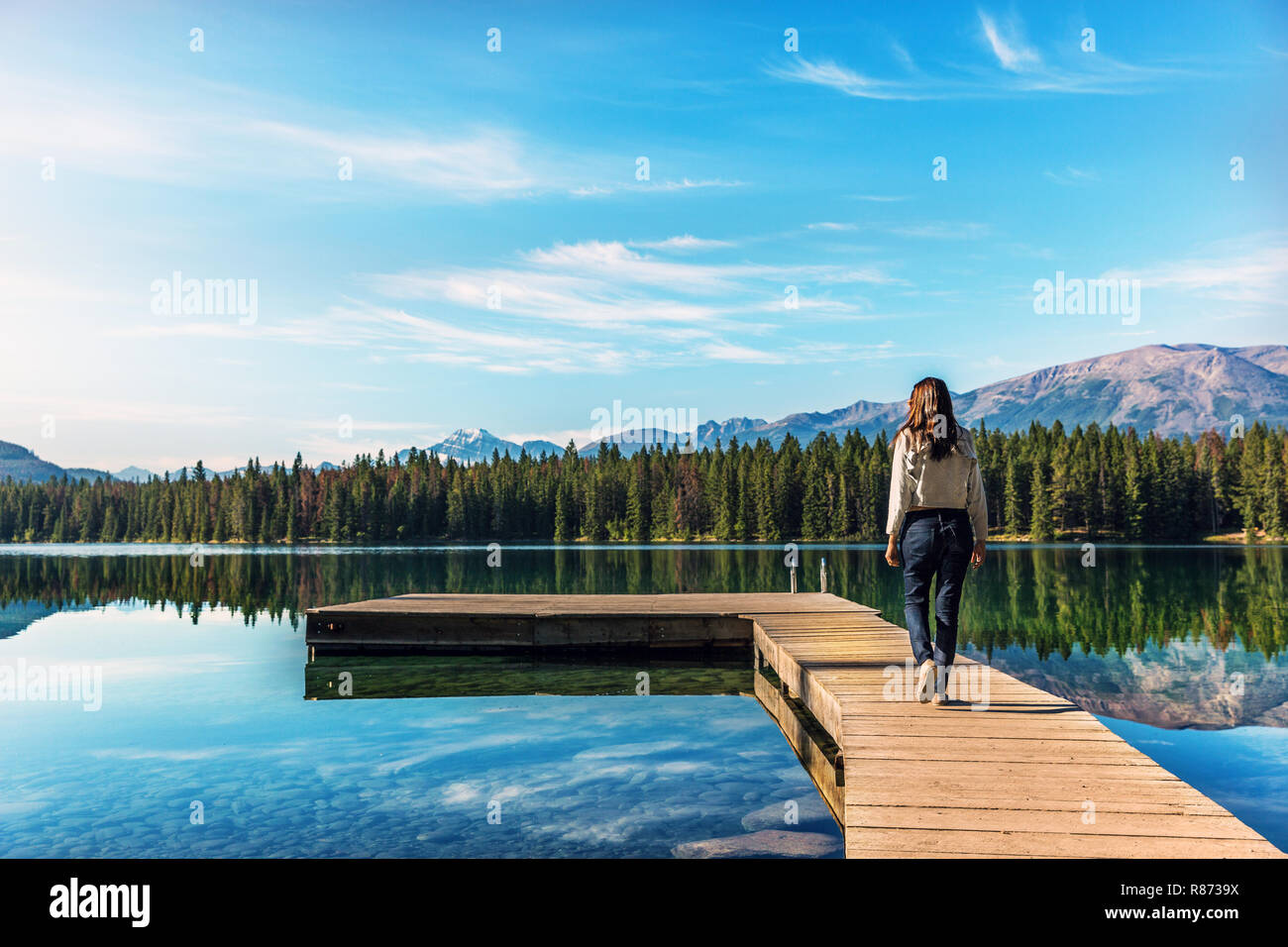 Young woman walking in a wood platform inside a lake with water ...