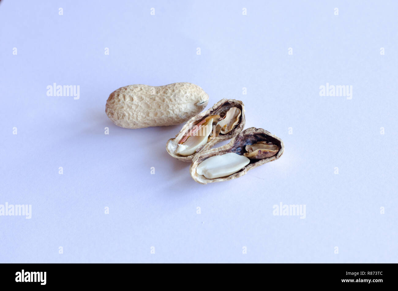 Peanuts on display on white background. One of them cracked with one ...