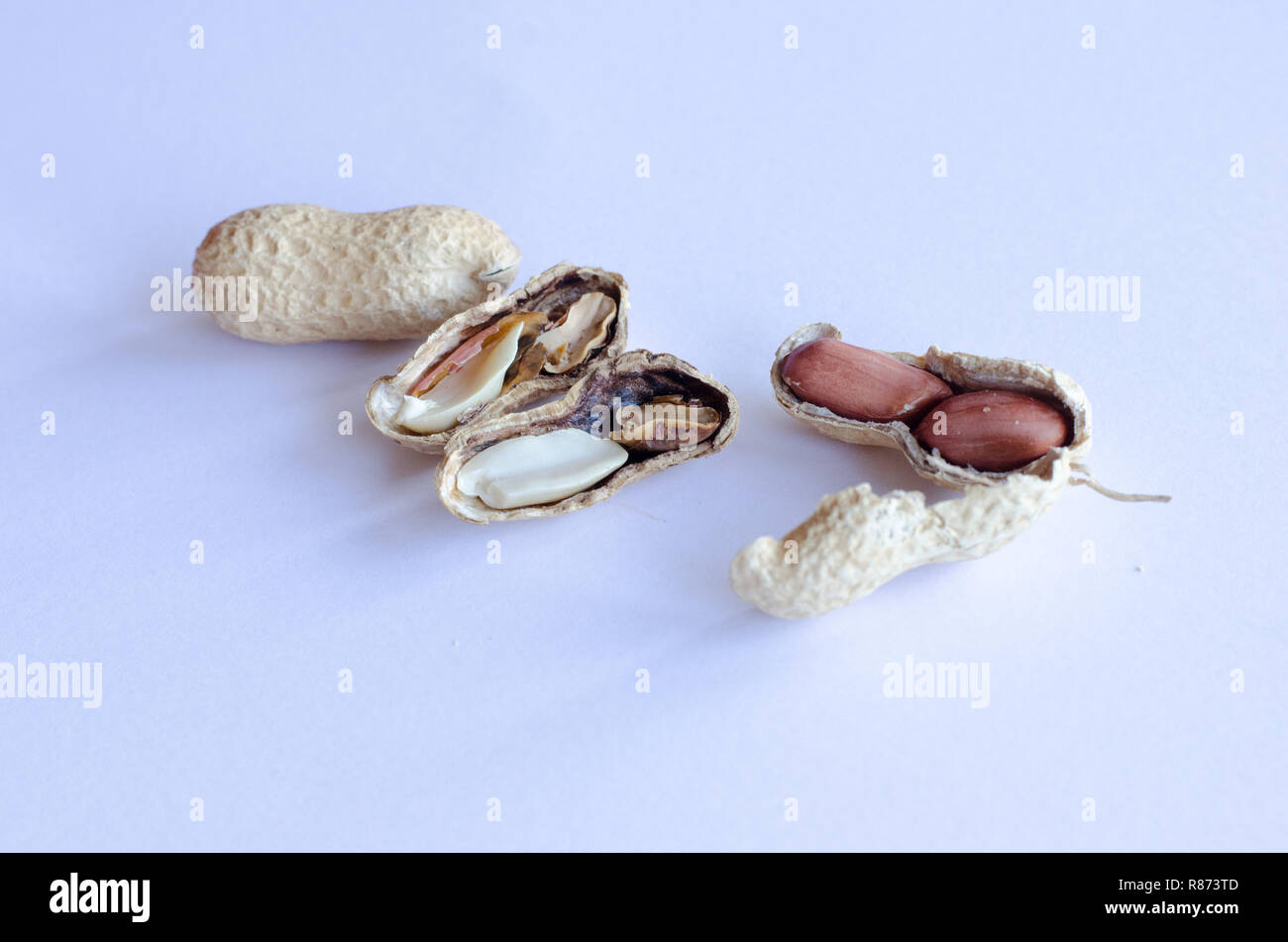 Peanuts on display on white background. One of them cracked with one ...