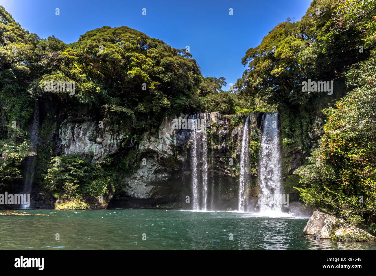 A waterfall in the island of Jeju in South Korea in a blue sky day ...