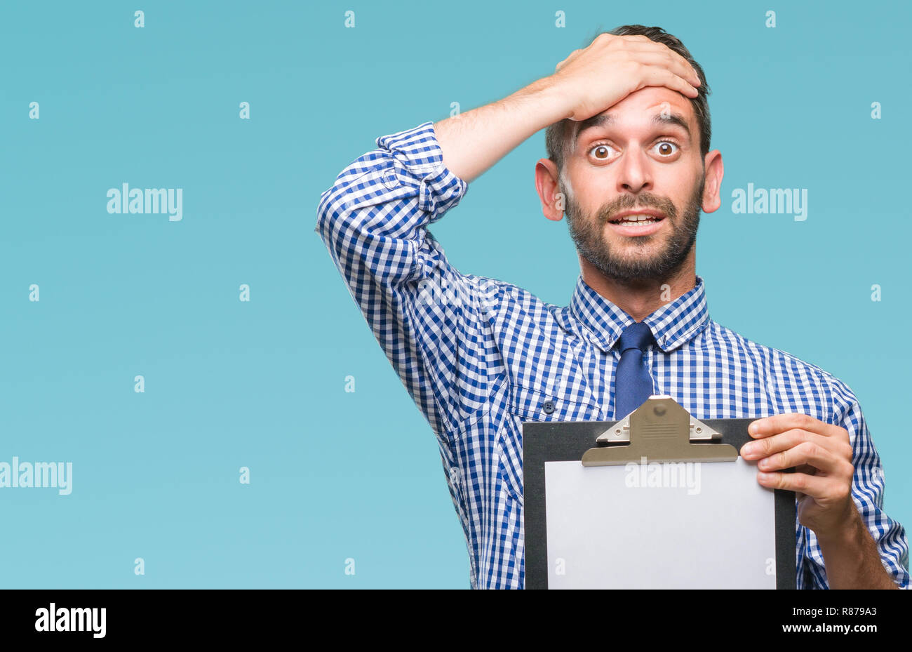 Young handsome business man holding clipboard over isolated background ...