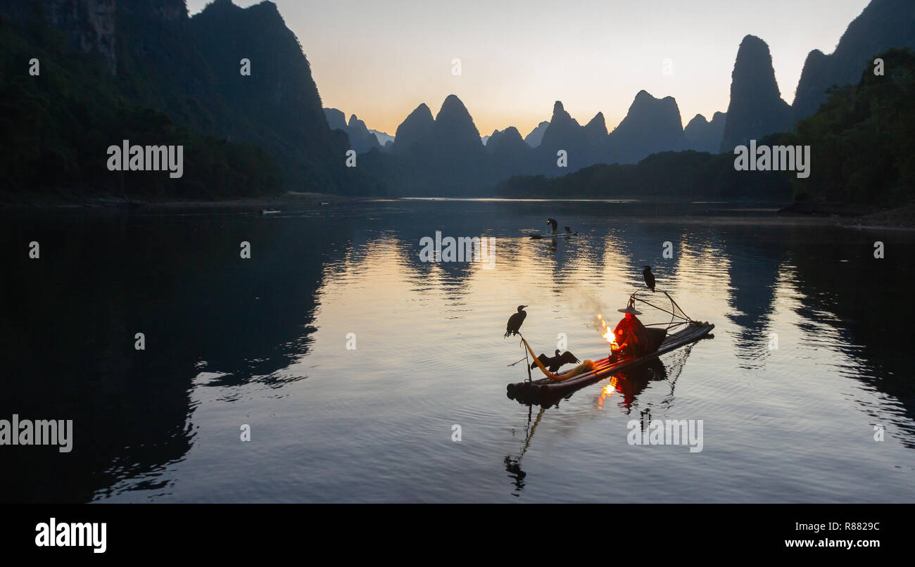 Cormorant fisherman on raft in lake in Guilin, China, with three ...
