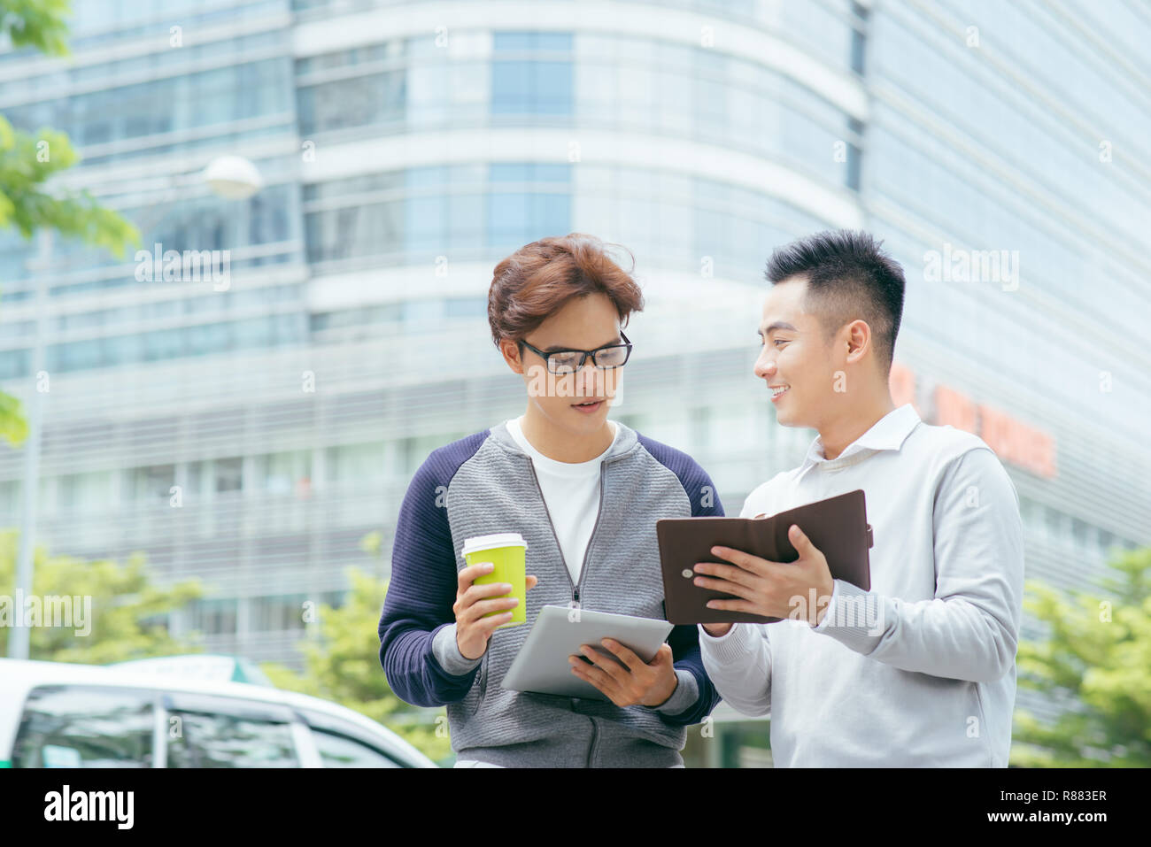 Closeup of two smiling business men using tablet computer and walking ...