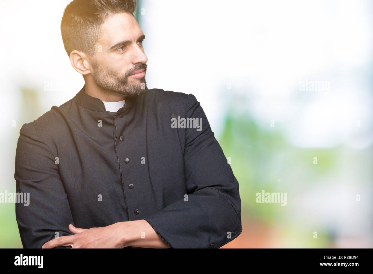 Young Christian priest over isolated background smiling looking to the ...