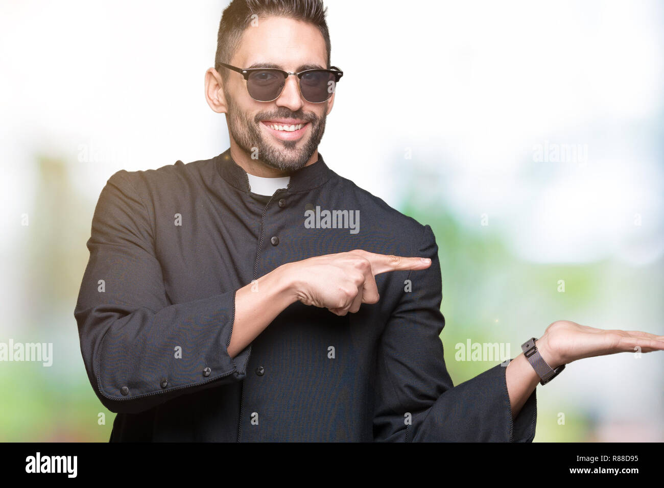 Young Christian priest wearing sunglasses over isolated background ...
