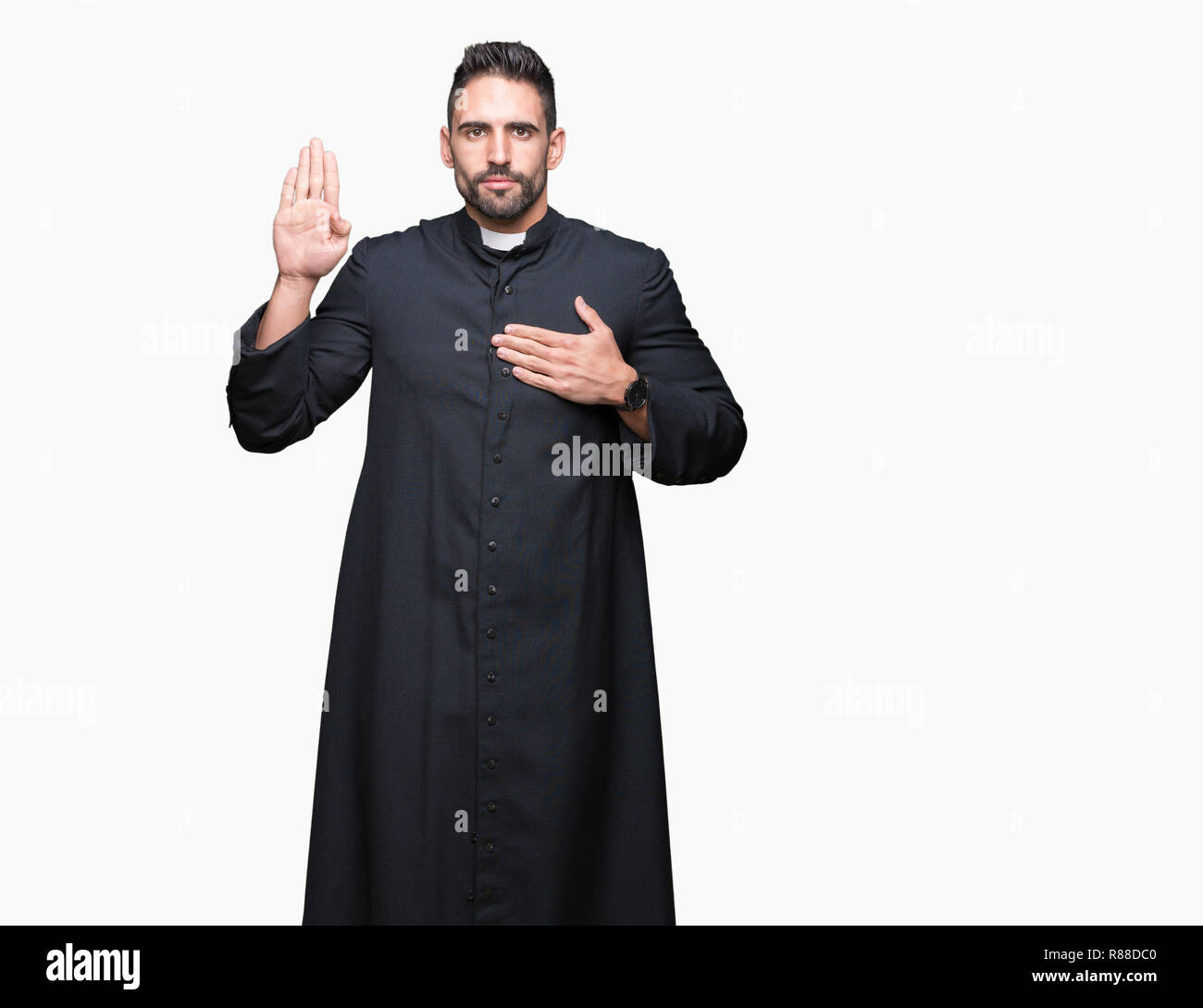 Young Christian priest over isolated background Swearing with hand on ...