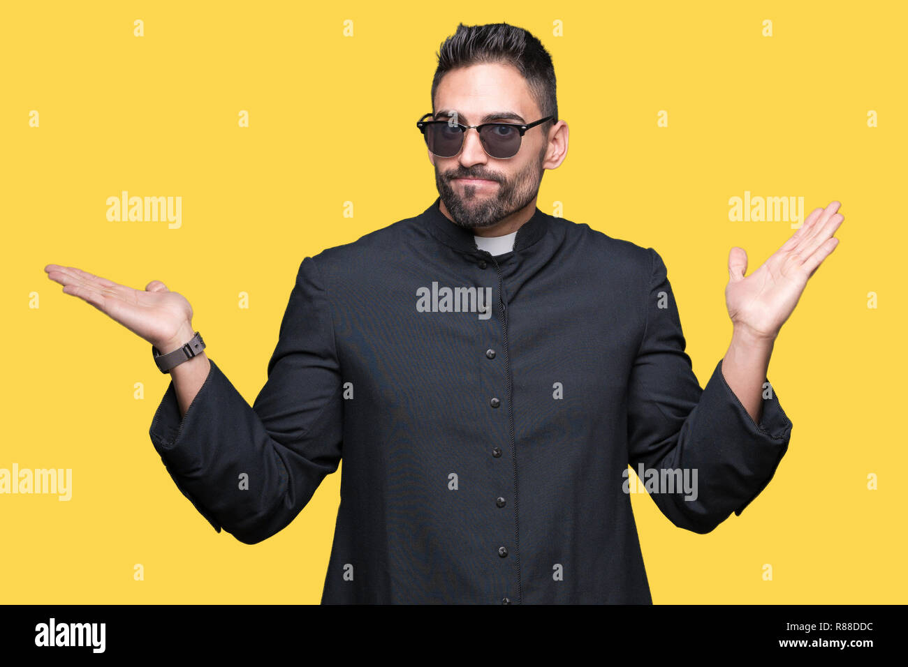Young Christian priest wearing sunglasses over isolated background ...