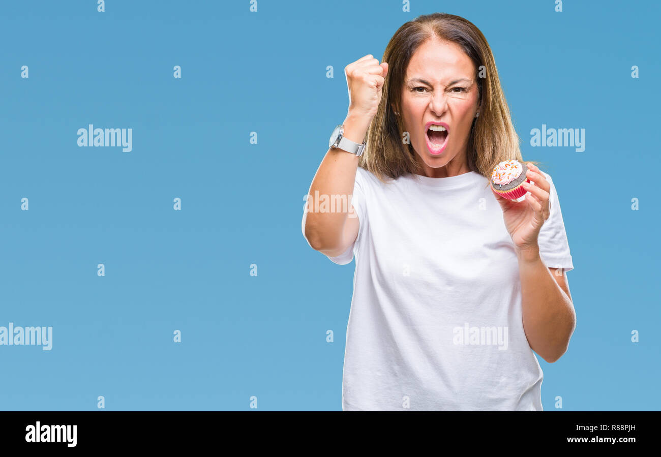 Middle age hispanic woman eating cupcake over isolated background ...