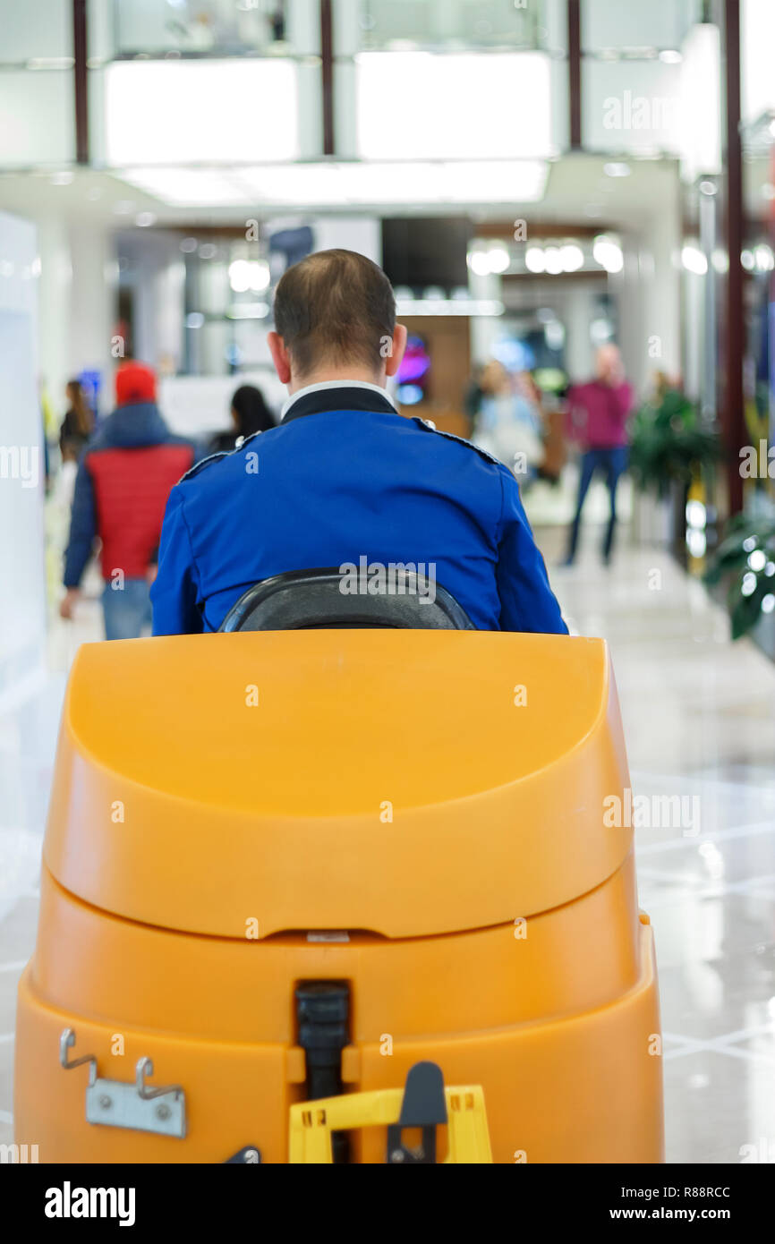 Cleaner in blue uniform on a sweeper in a shopping center Stock Photo ...