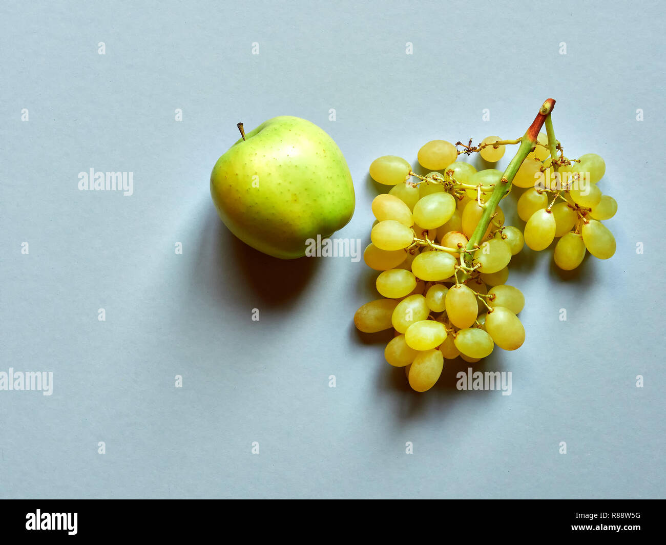 Green apple and bunch of green grapes isolated in studio against a grey ...