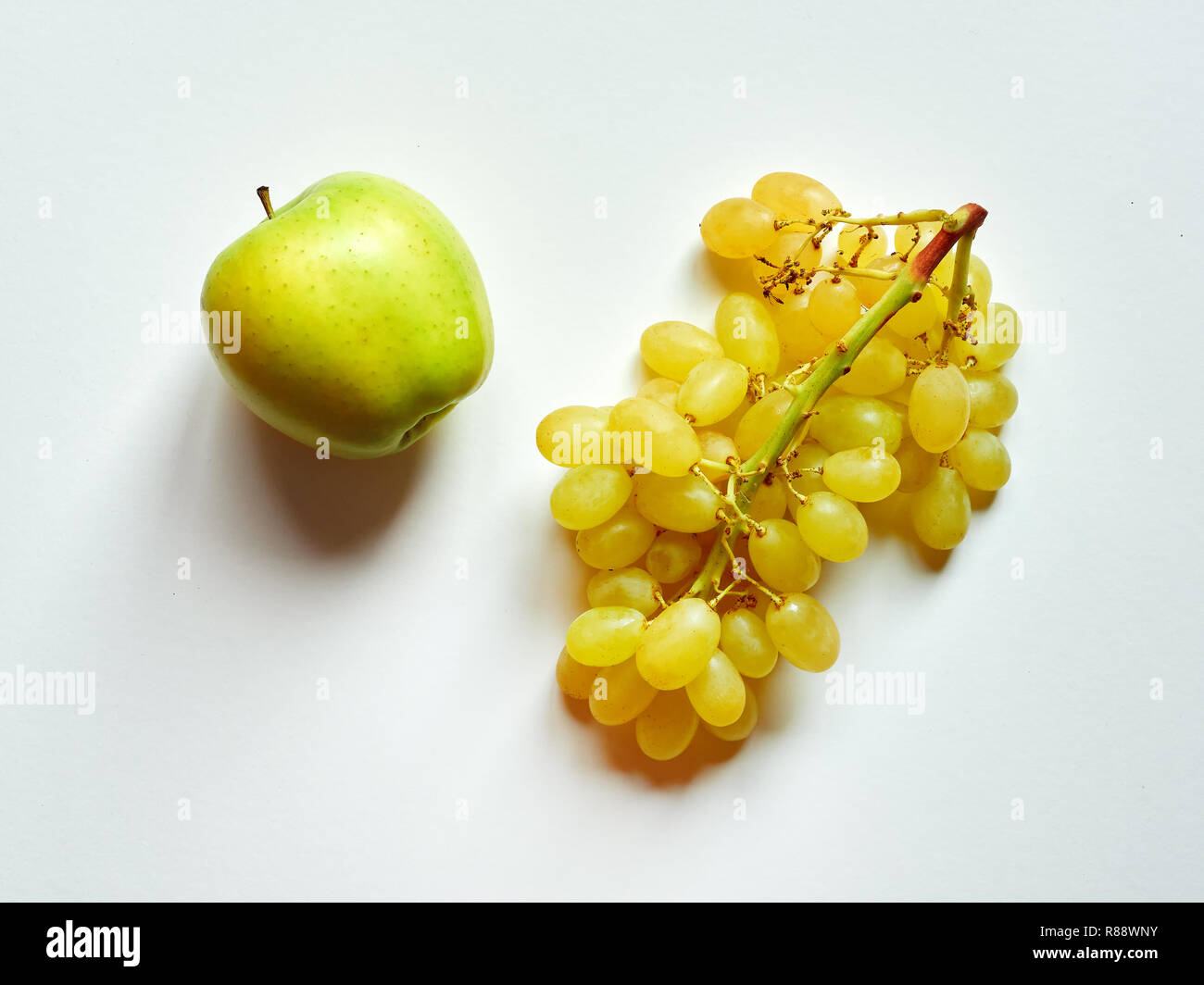 Green apple and bunch of green grapes isolated in studio against a ...
