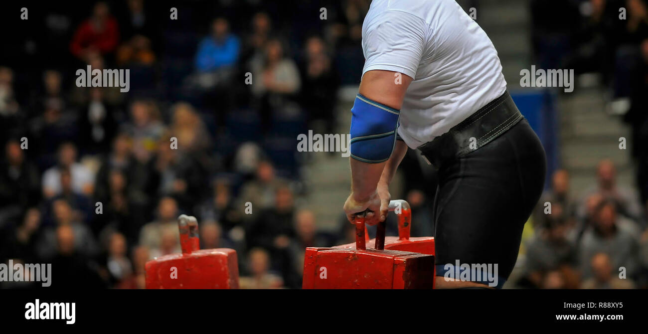 muscular sportsman doing farmer's walk exercise during his competition ...