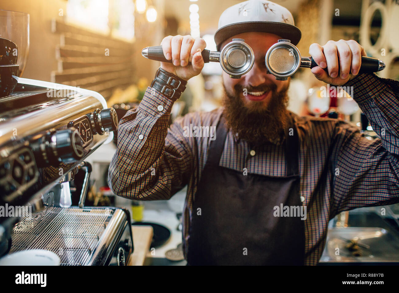 Funny picture of bearded barista in apron holding tow cezve and cover ...