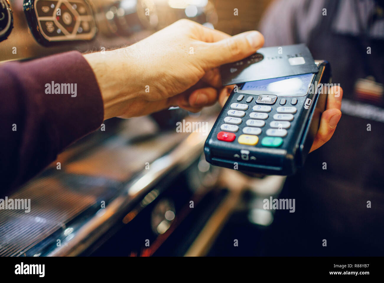 One hand hold machine for cards white another hold dark card for paying ...