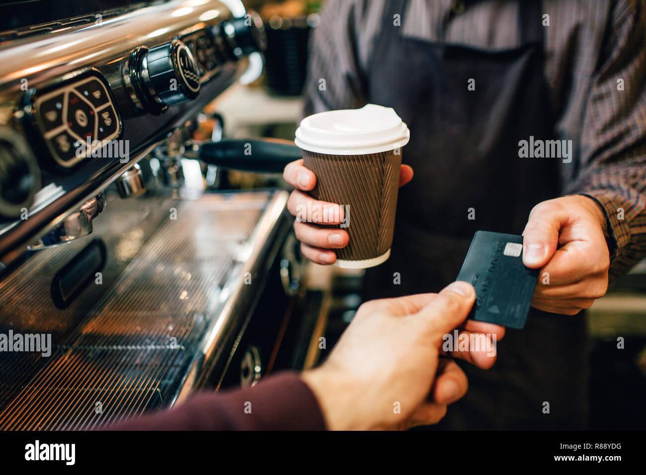 Picture of barista stand at coffee machine and hold cup of coffee. He ...