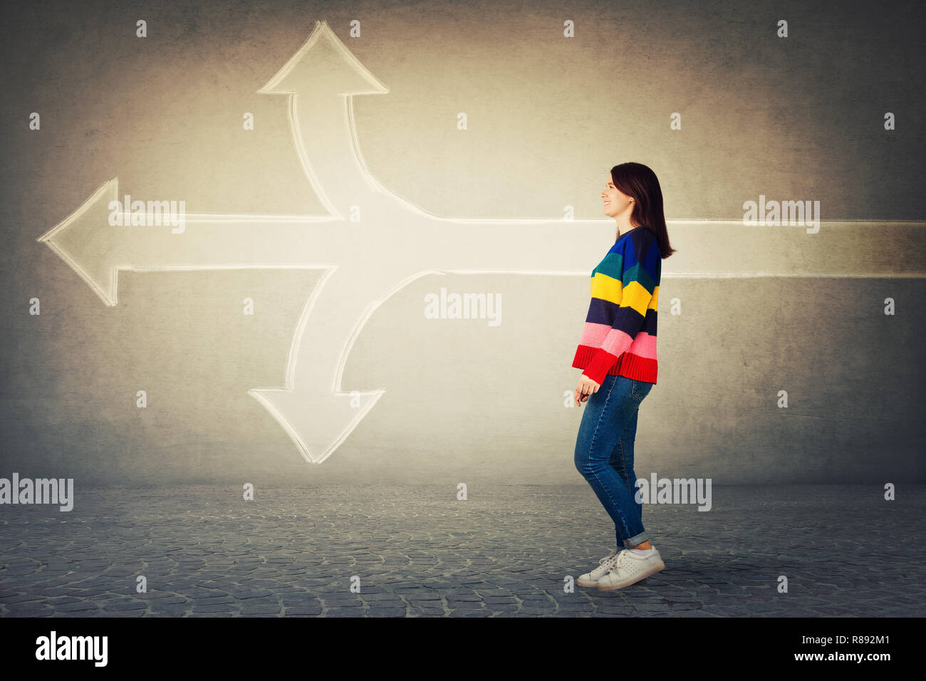 Happy positive young woman choosing the direction to go as arrows ...