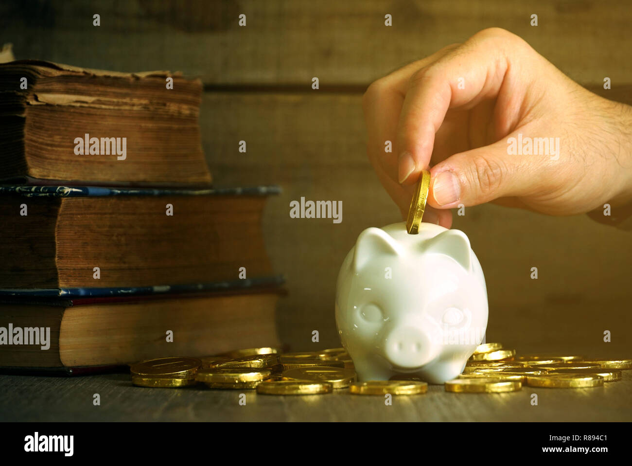 Hand fill coin to white piggy save with gold coin on working table ...