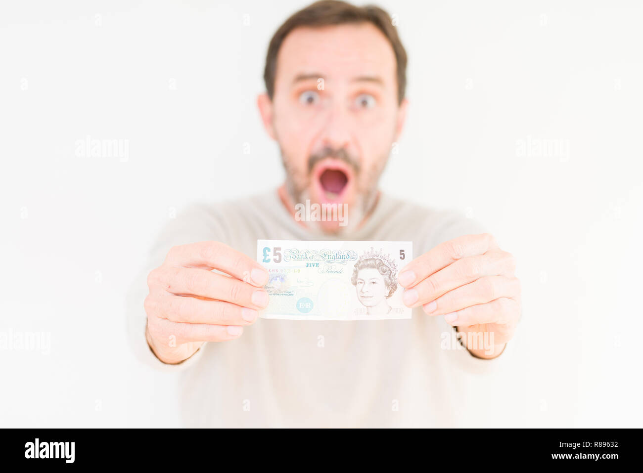 Senior man holding five pounds bank note over isolated background ...