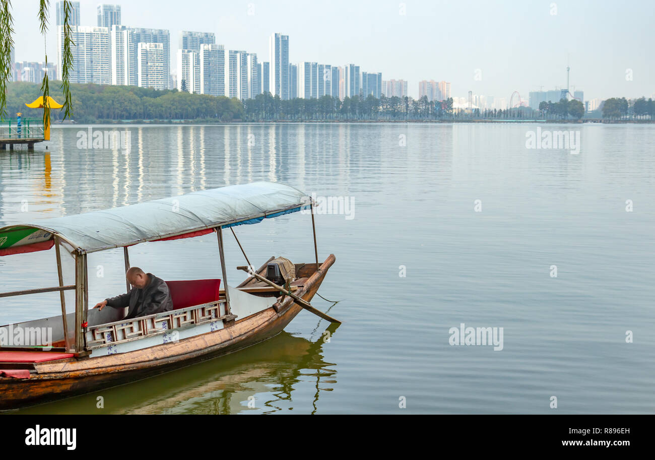Chinese man asleep on a covered raft on East Lake, China, with Wuhan ...