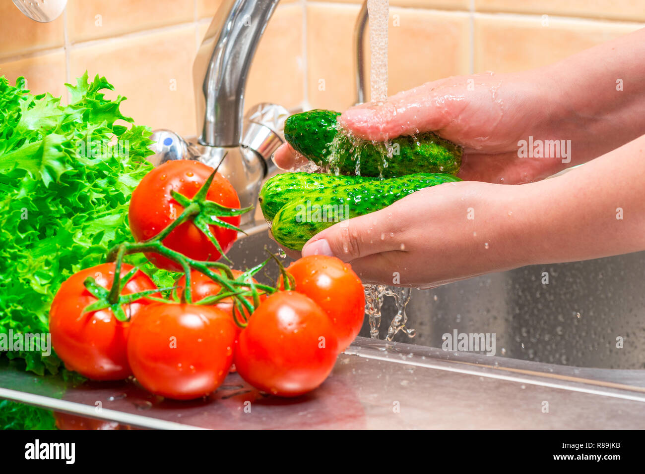 washing cucumbers and vegetables in the kitchen under running water ...