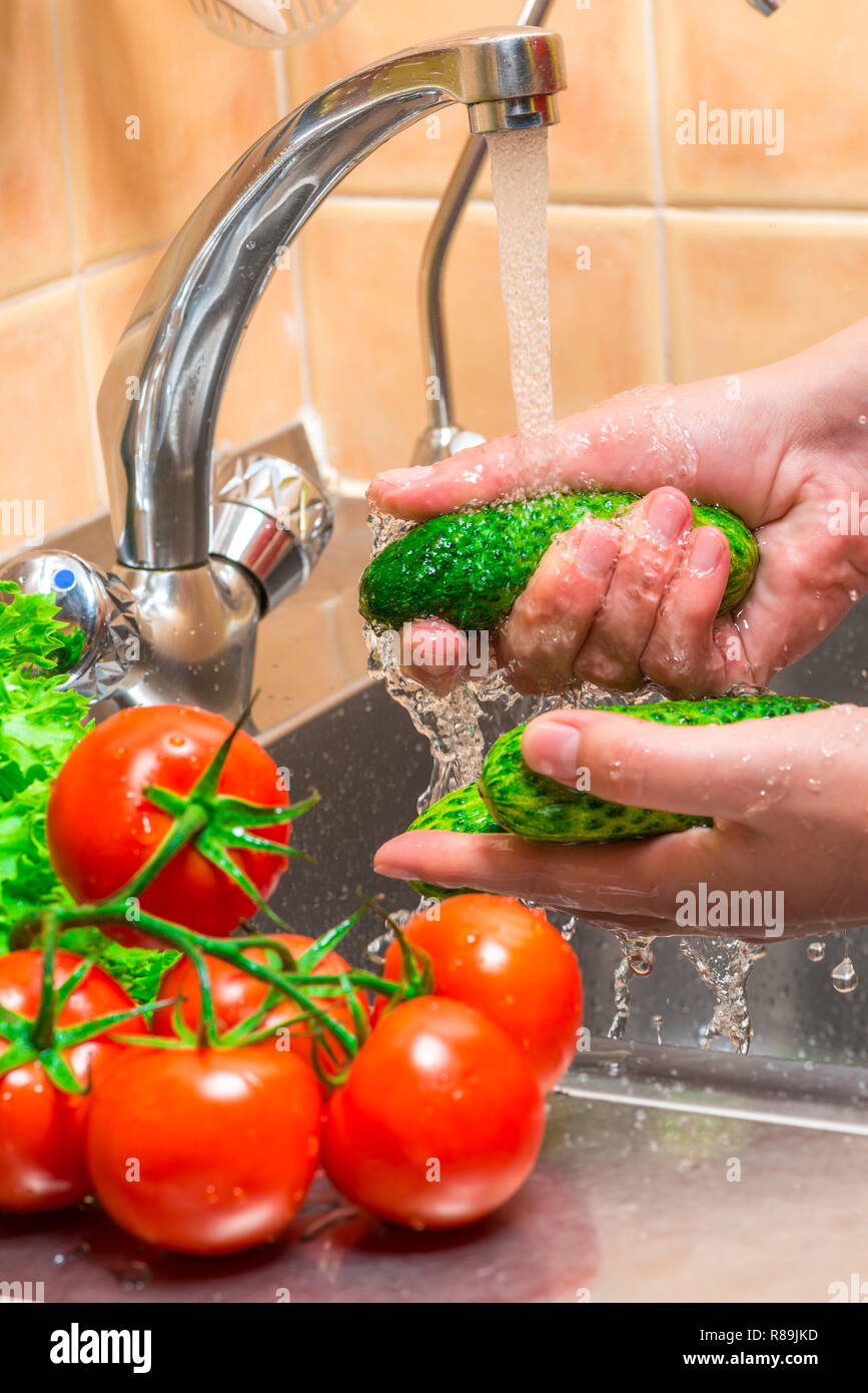 women's hands washing vegetables in the kitchen under running water ...