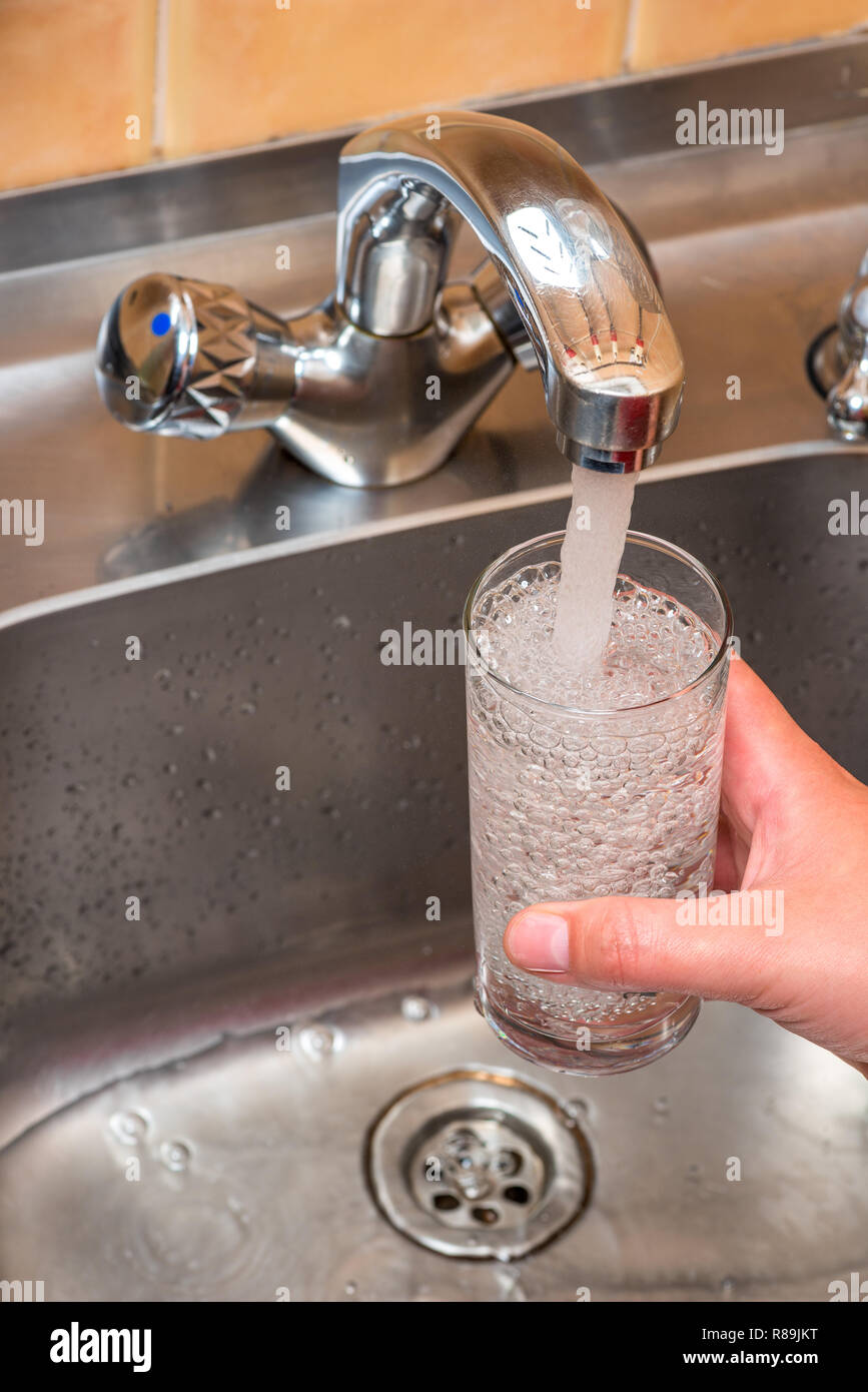 a set of clean drinking water from a kitchen tap into a glass, hand ...