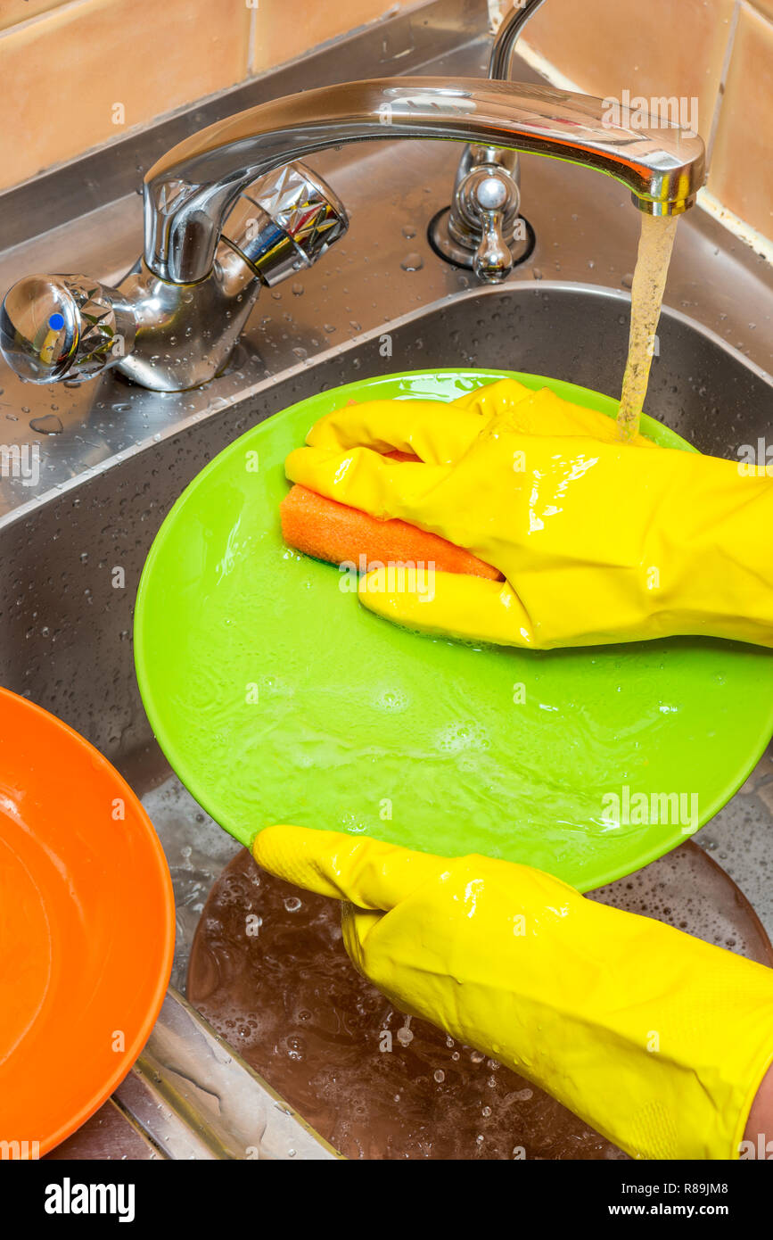 washing dishes in the kitchen with gloved hands Stock Photo - Alamy