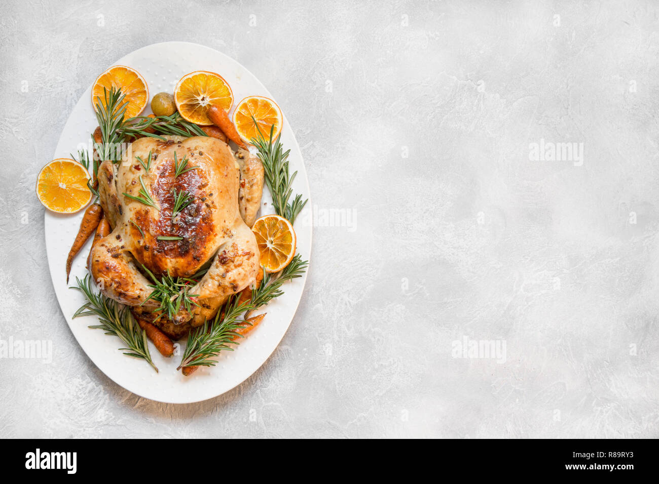 Traditional roasted chicken garnish orange, carrot, and rosemary on ...