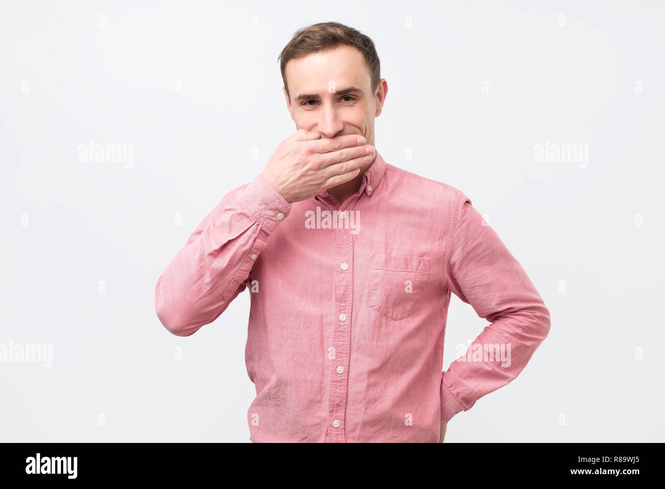 Young Laughing Excited Happy Man Covering Mouth Trying Not To Laugh