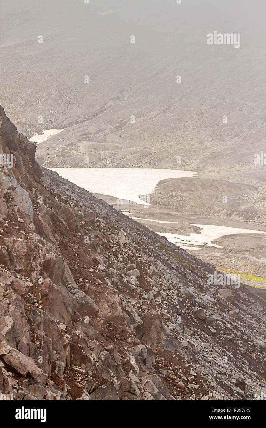 crumbling rocky mountain sides with snow fields in valley Stock Photo ...