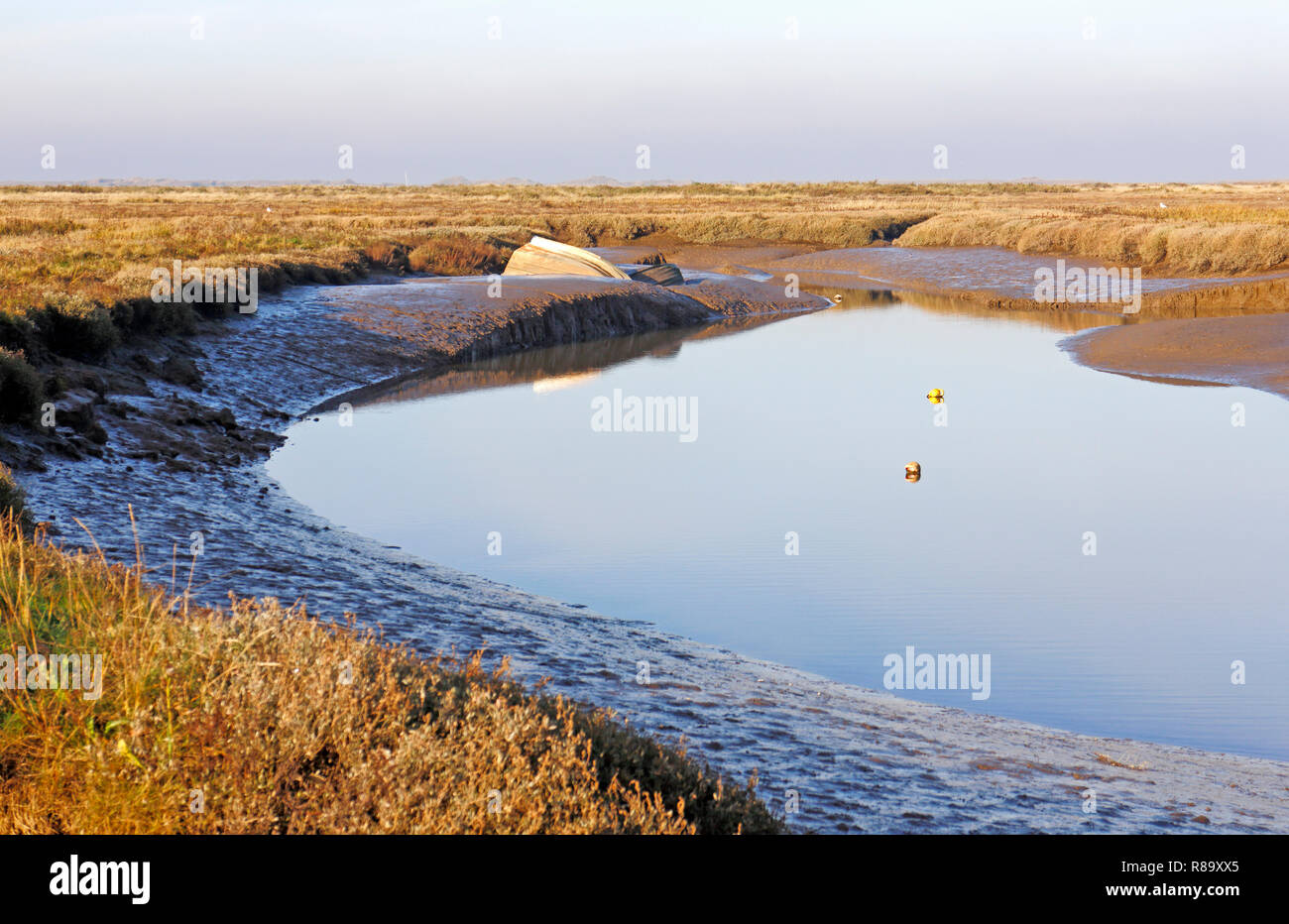 A creek in salt marshes with abandoned boat in North Norfolk at ...