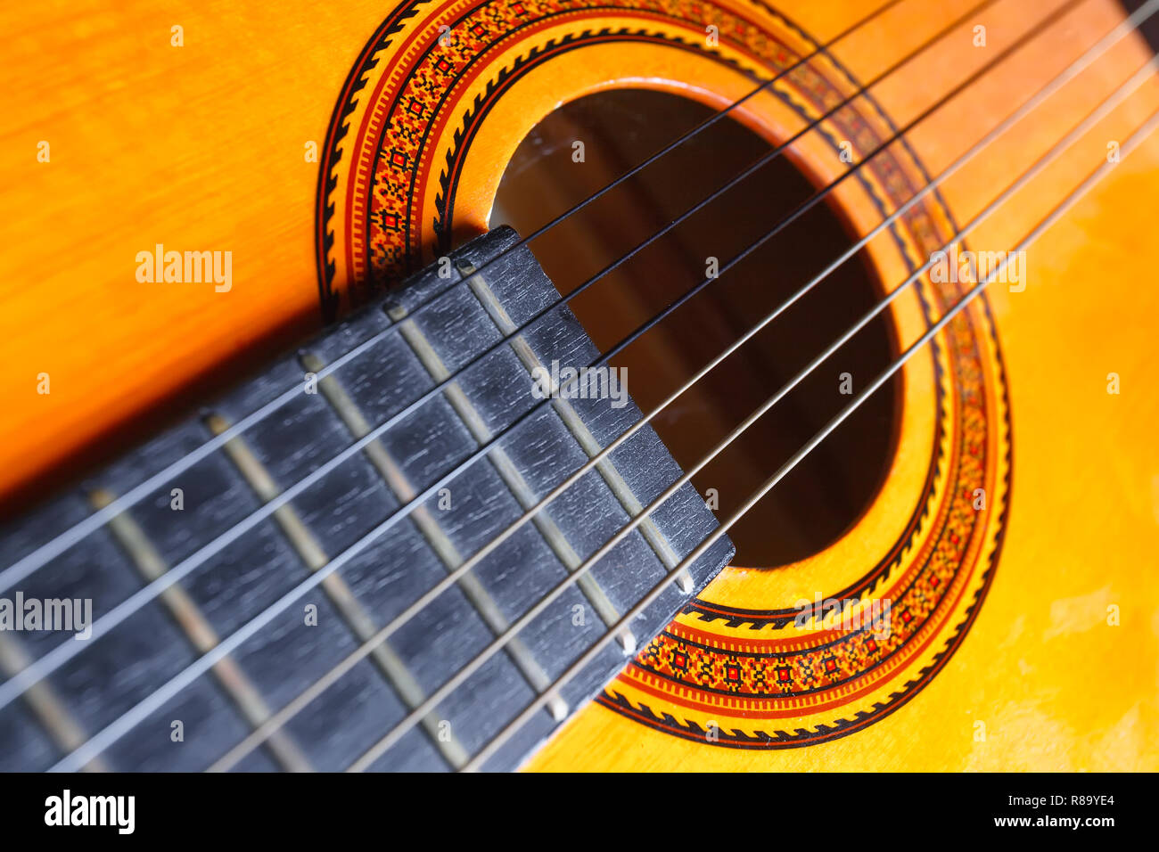 Strings, rose and neck of a yellow and orange guitar. Musical ...