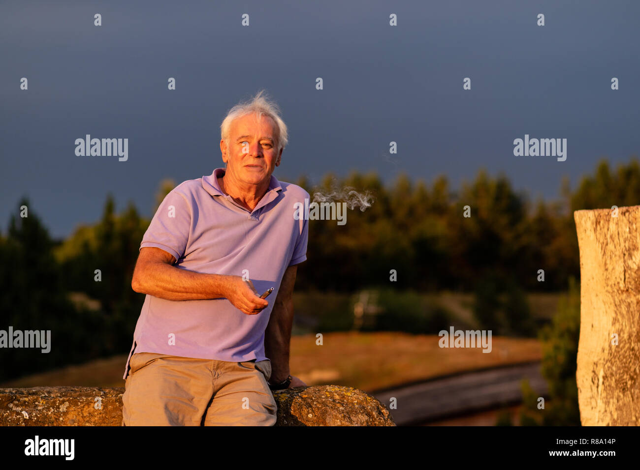 A handsome older man puffing on an e-cigarette with copy space on the ...
