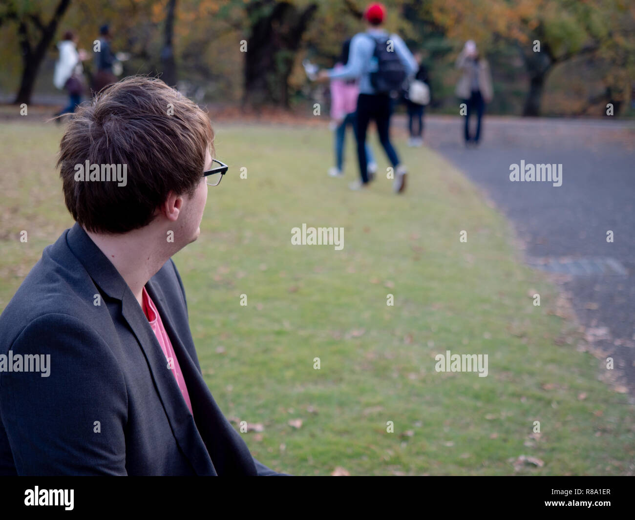 A lonely man looking wistfully towards people with friends Stock Photo ...